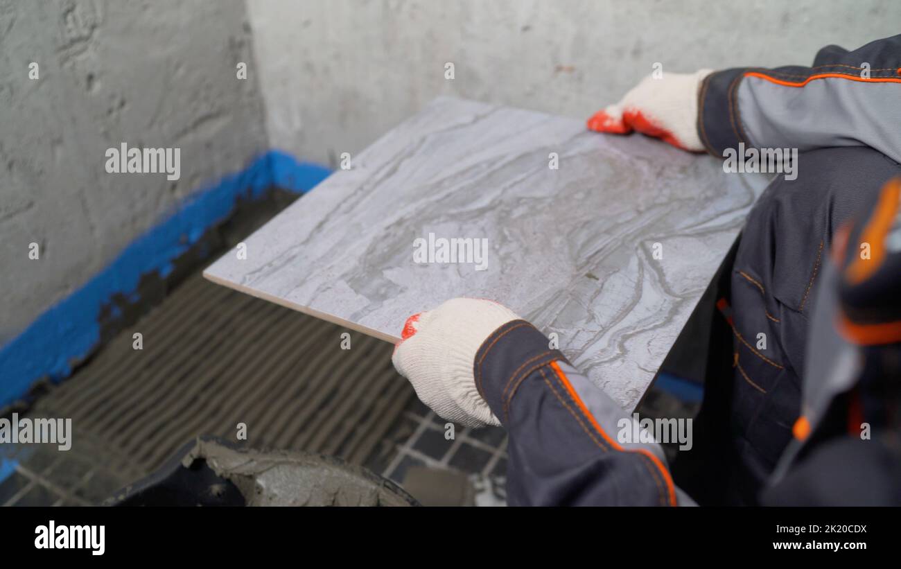 Hands working placing ceramic floor tiles. Laying tiles on the floor ...