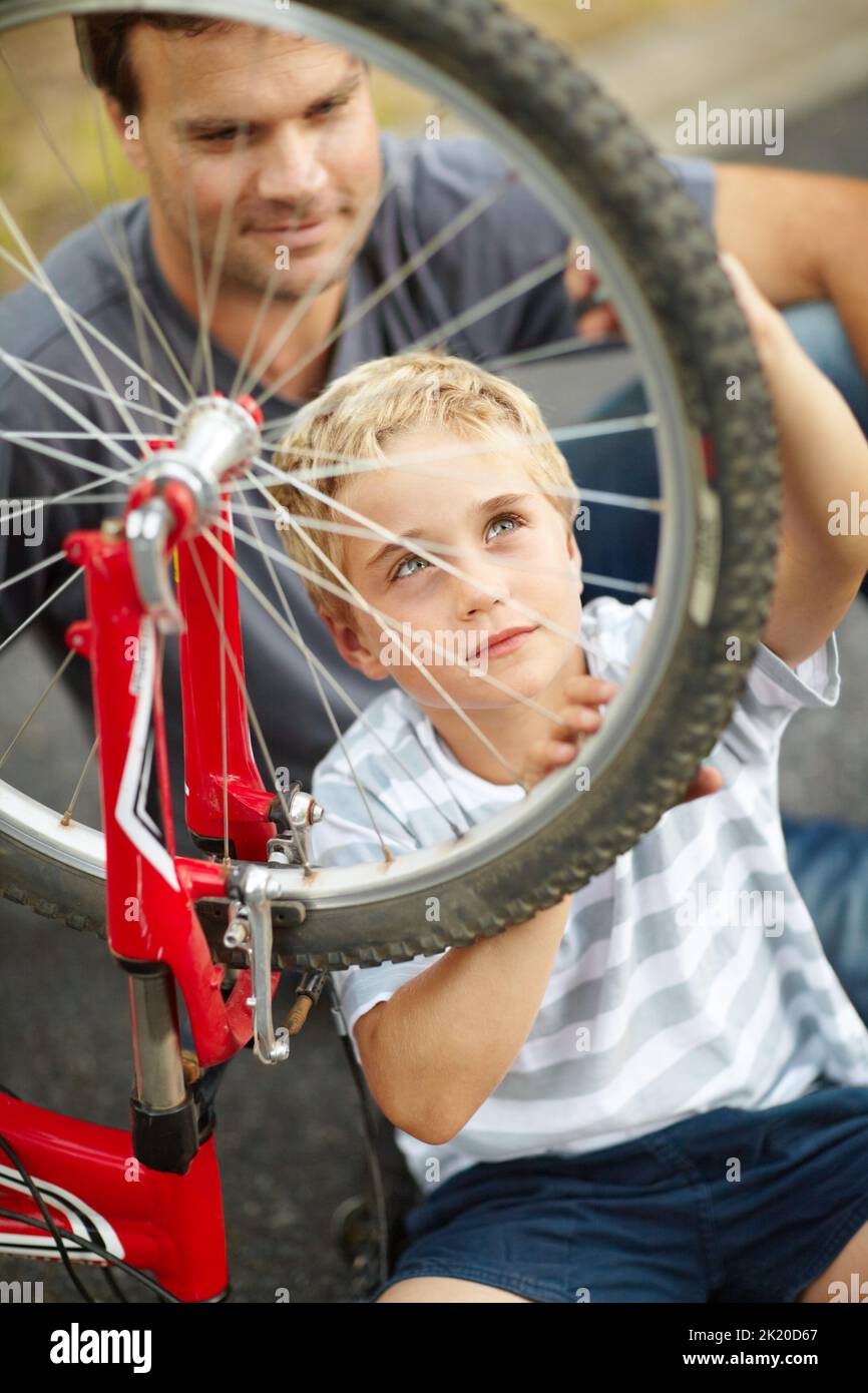 A new learnt skill he wont forget. Young father teaching his son how to change a bike puncture ...