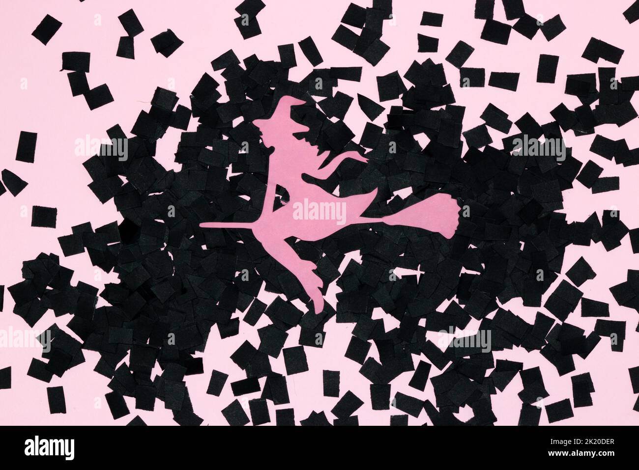 pink paper witch on broom on black part of black and pink background ...