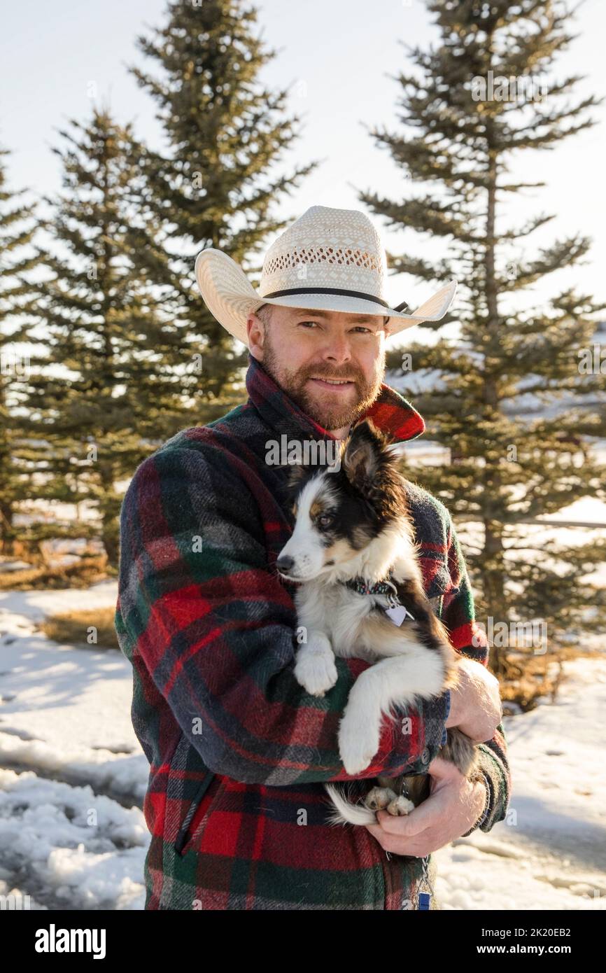 Portrait male rancher holding dog on snowy ranch Stock Photo - Alamy