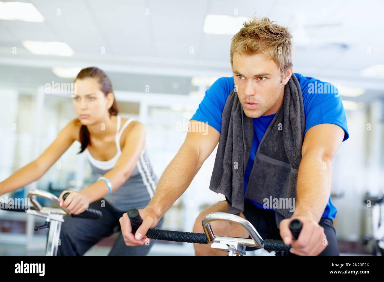 Spinning exercise. Young man training on exercise bike with woman in ...