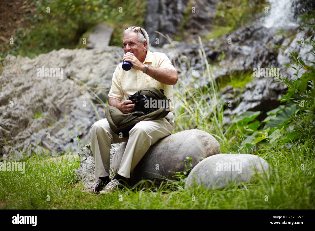 Nothing like a walk in nature...a senior man having a water break while ...