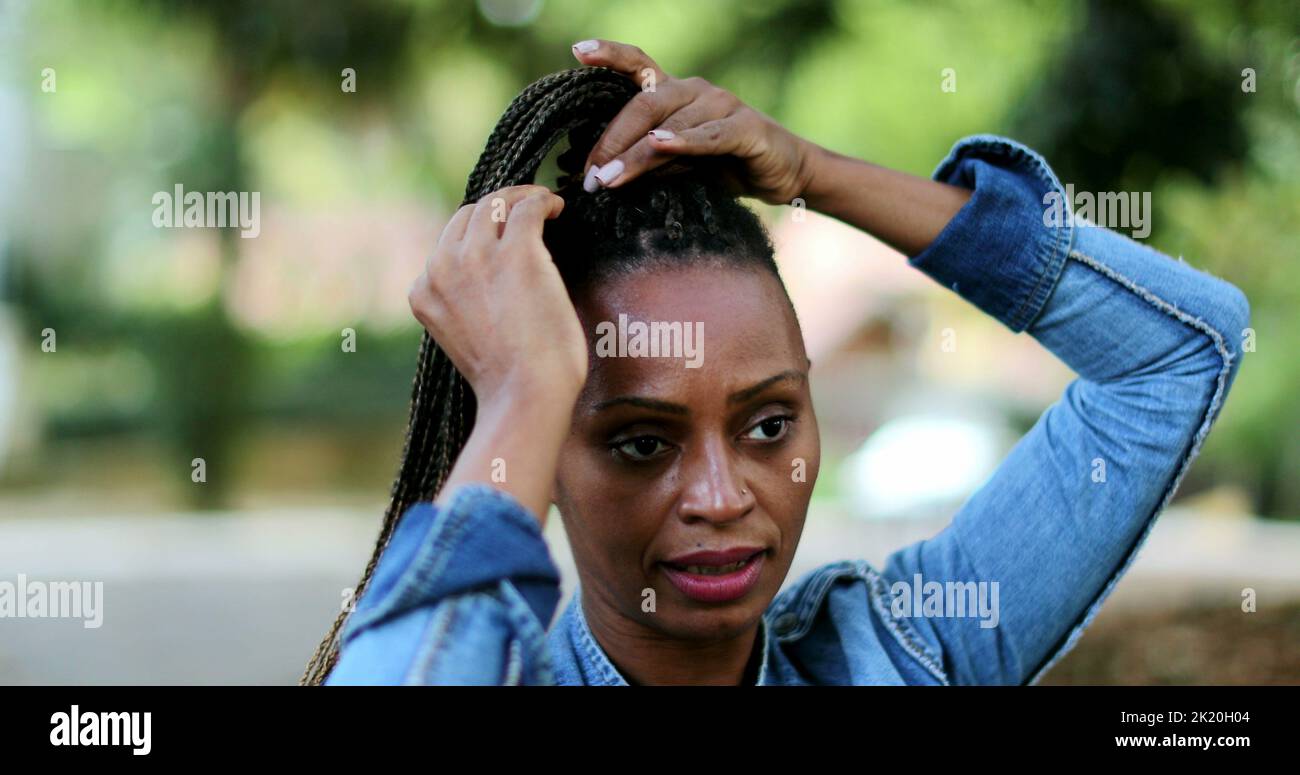 African woman adjusting dread hair outside Stock Photo - Alamy