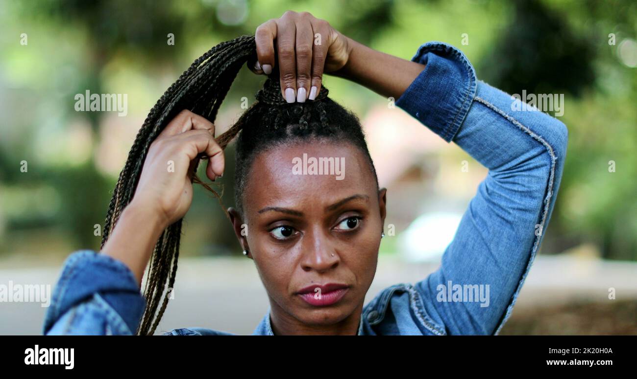 African woman adjusting dread hair outside Stock Photo - Alamy
