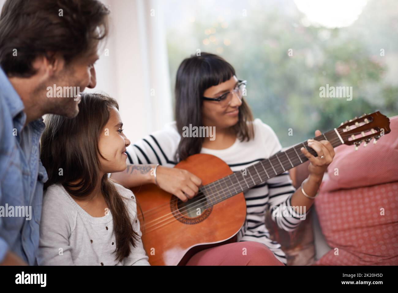 Mommys got the guitar. a woman playing the guitar while sitting with ...