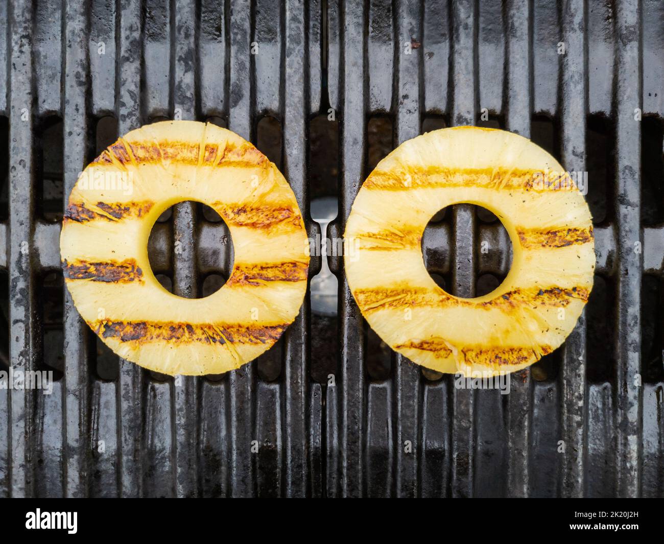 Two pineapple rings cooking on a barbeque grill Stock Photo - Alamy