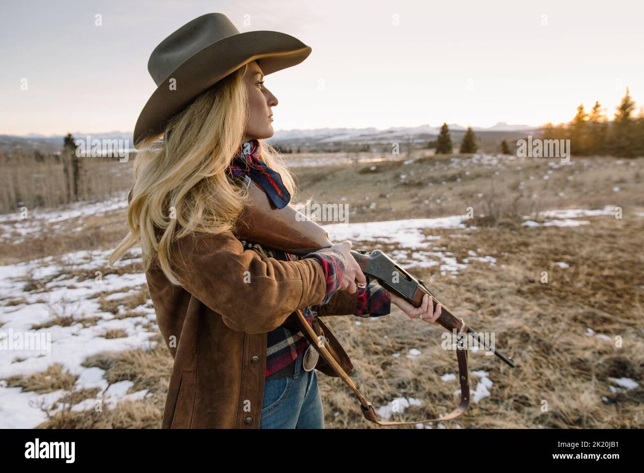 Female hunter with rifle in snowy field at sunset Stock Photo - Alamy