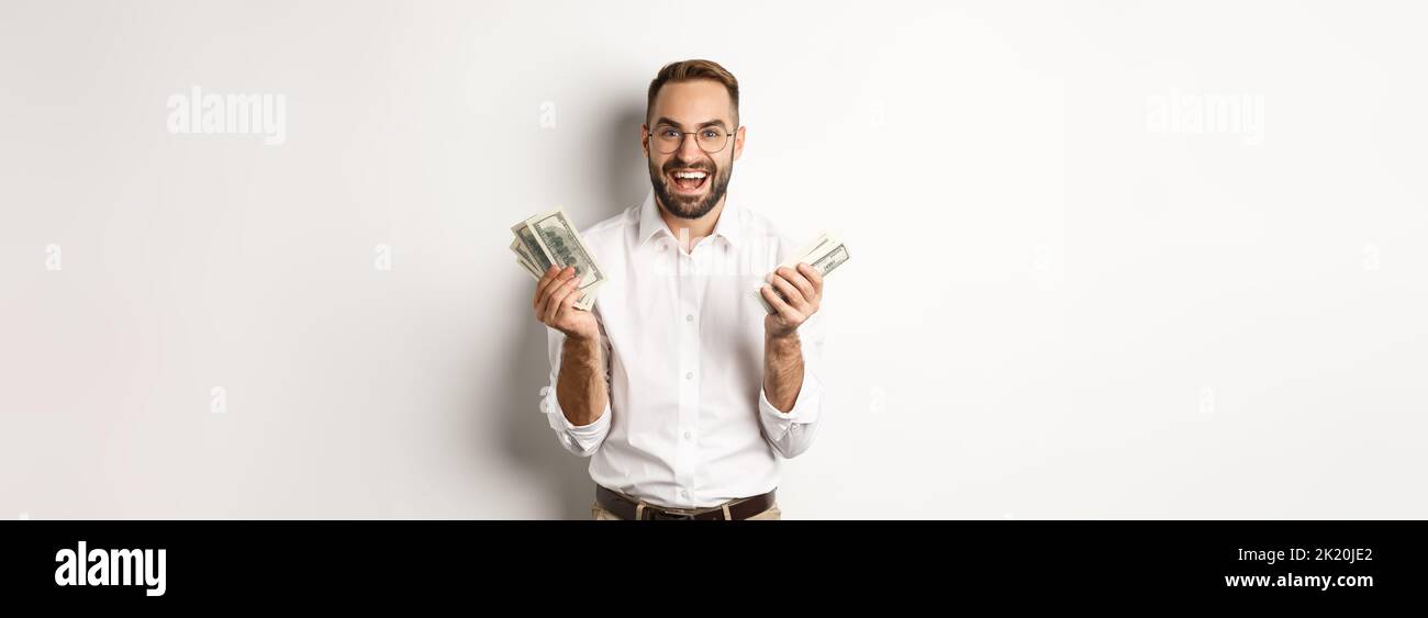 Handsome successful business man counting money, rejoicing and smiling ...