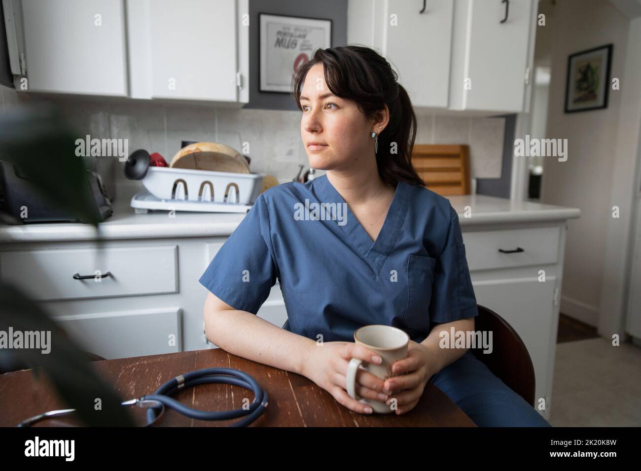 Nurse sitting in kitchen with coffee Stock Photo - Alamy