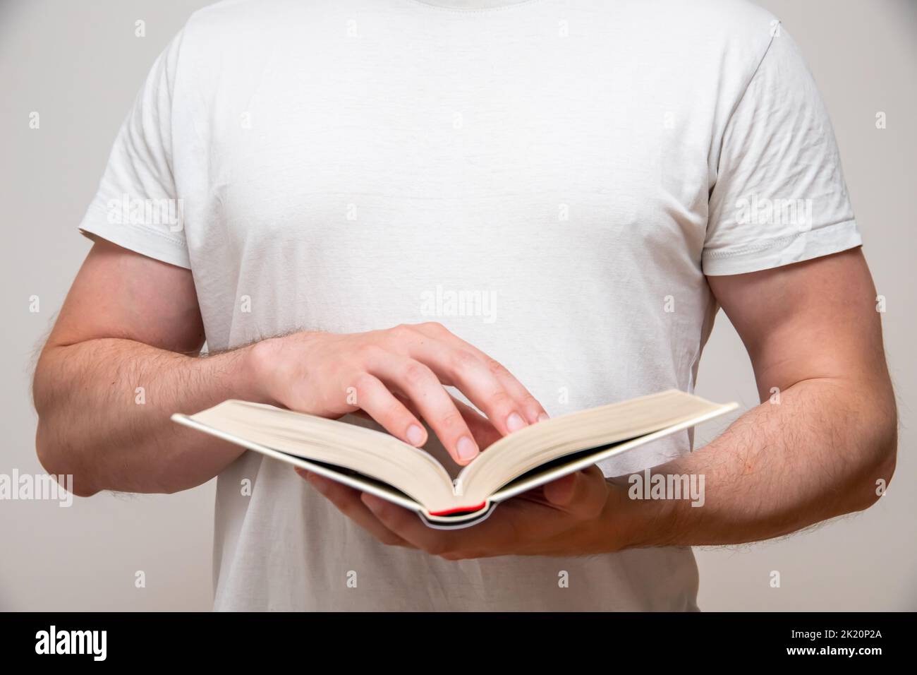 A person holding a book open on a random page on a plain background ...