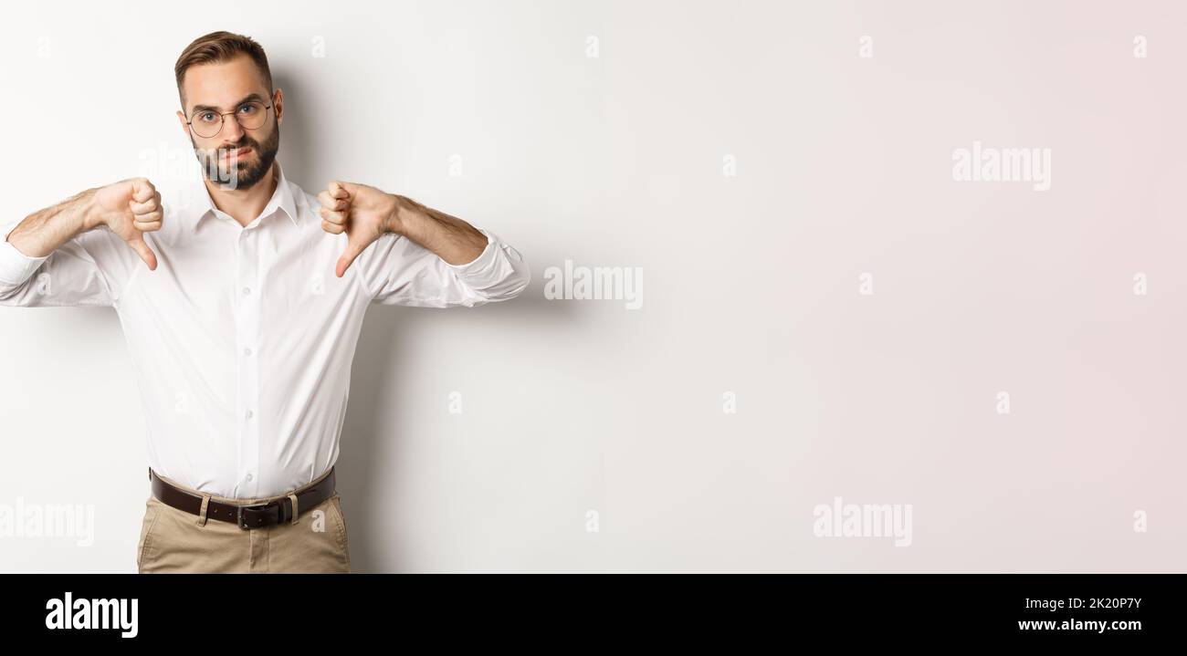 Displeased businessman in glasses showing thumbs down, dislike and ...