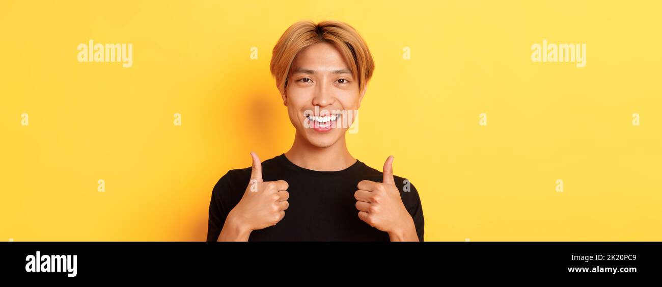 Close-up of satisfied, happy asian guy in black t-shirt, showing thumbs ...