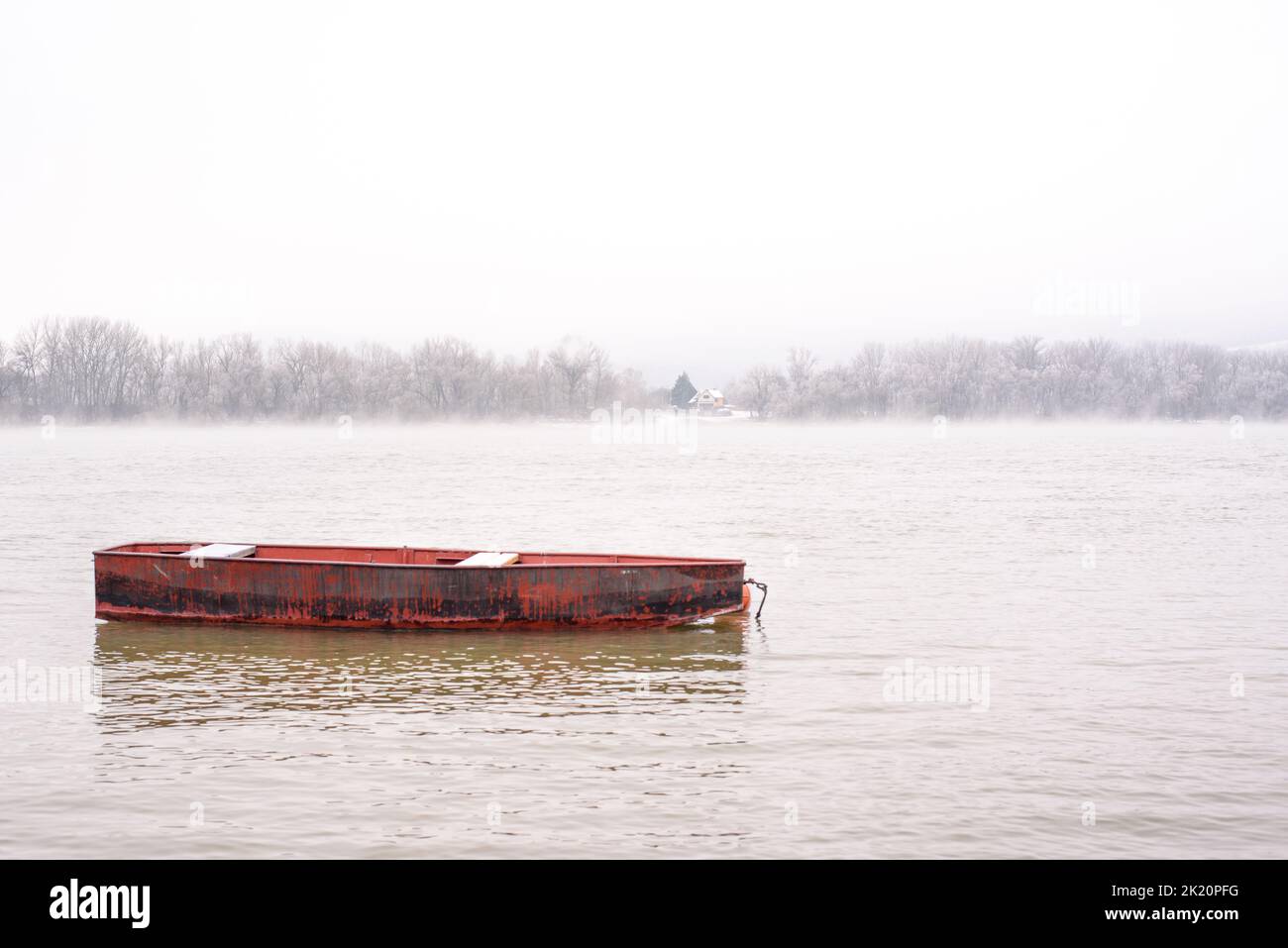 Empty red boat in misty river in winter Stock Photo - Alamy