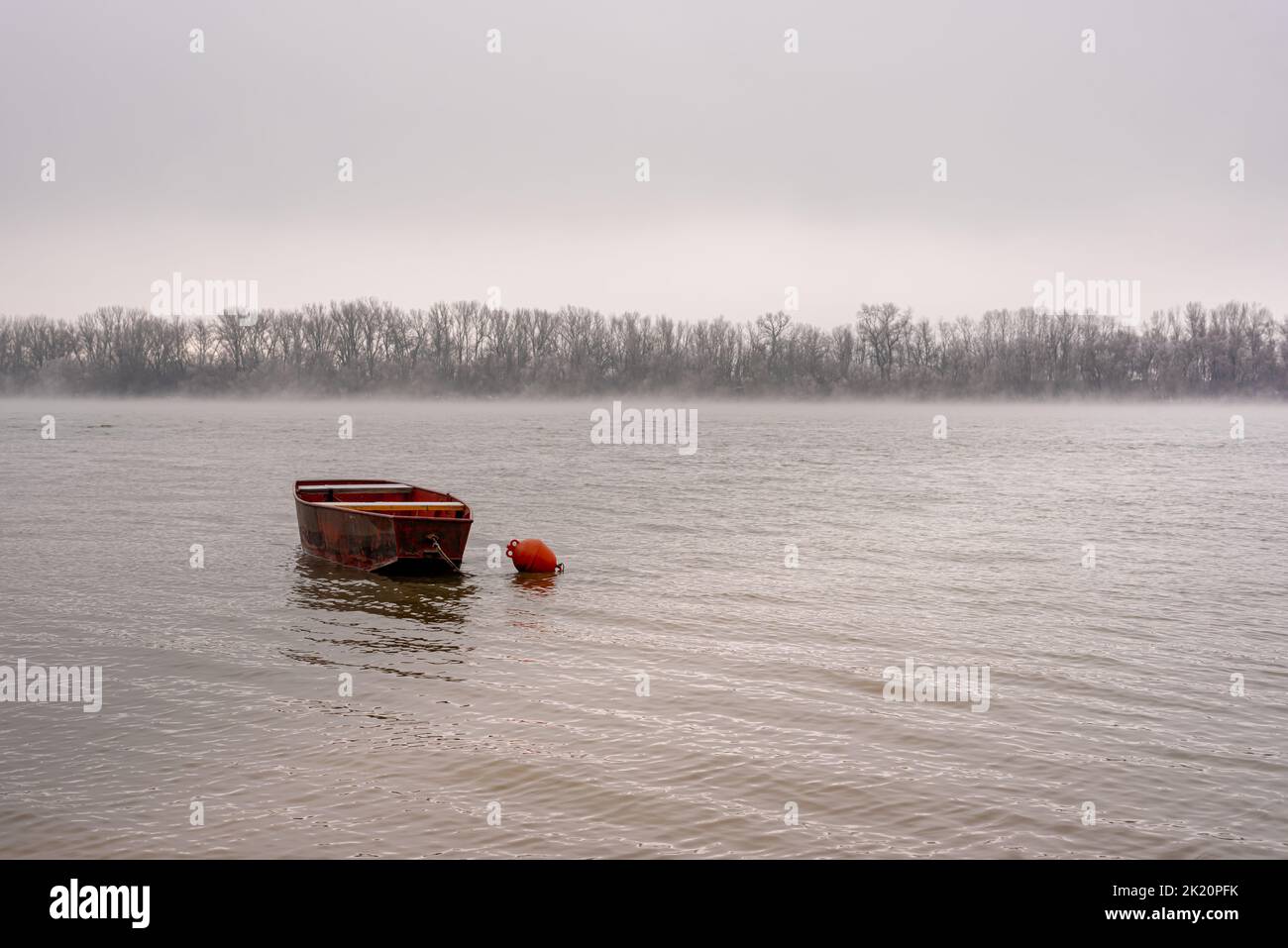 Empty red boat in misty river in winter Stock Photo - Alamy