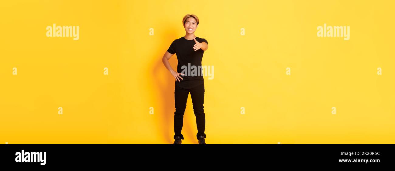 Full-length of friendly handsome korean guy with blond hair, extending ...