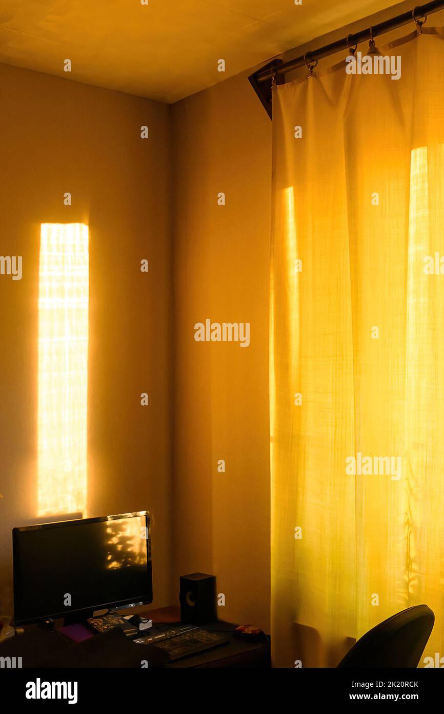 Sunbeams at sunset fall on computer desk in apartment. Ray of sun on ...