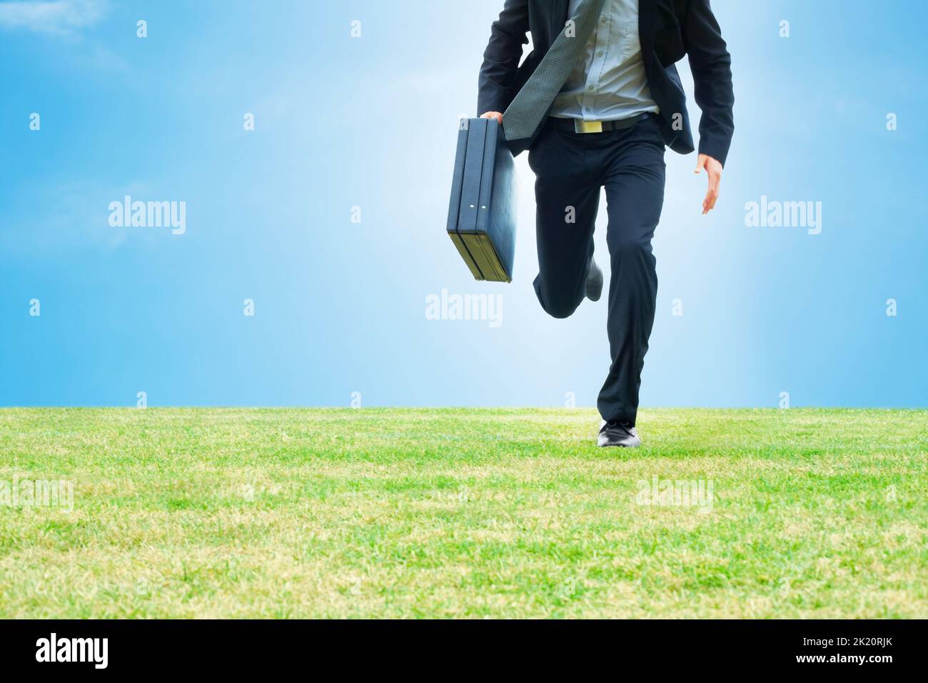 Business man running with a briefcase on a field. Cropped image of a ...