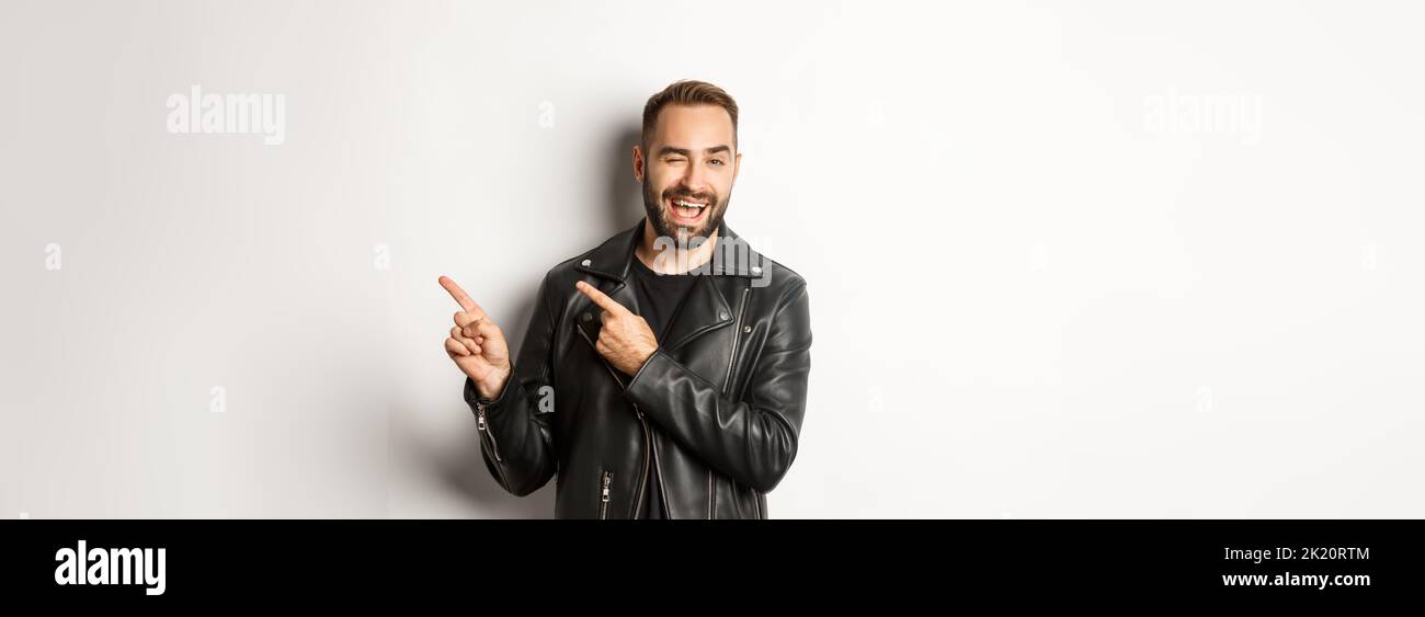 Cheeky guy in leather biker jacket, winking flirty and pointing at ...