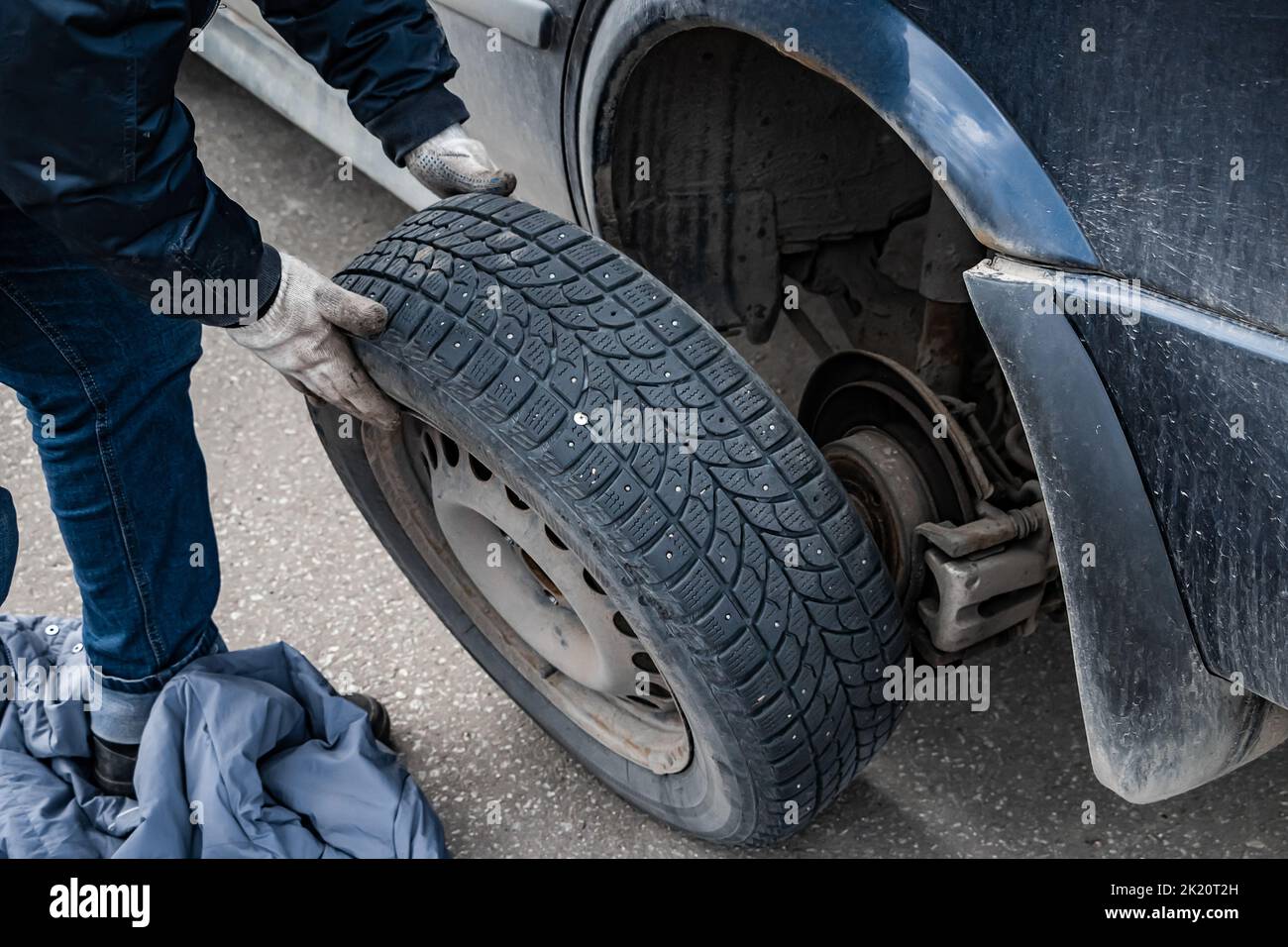 Auto mechanic changes wheel on old car. Man changes punctured tire ...