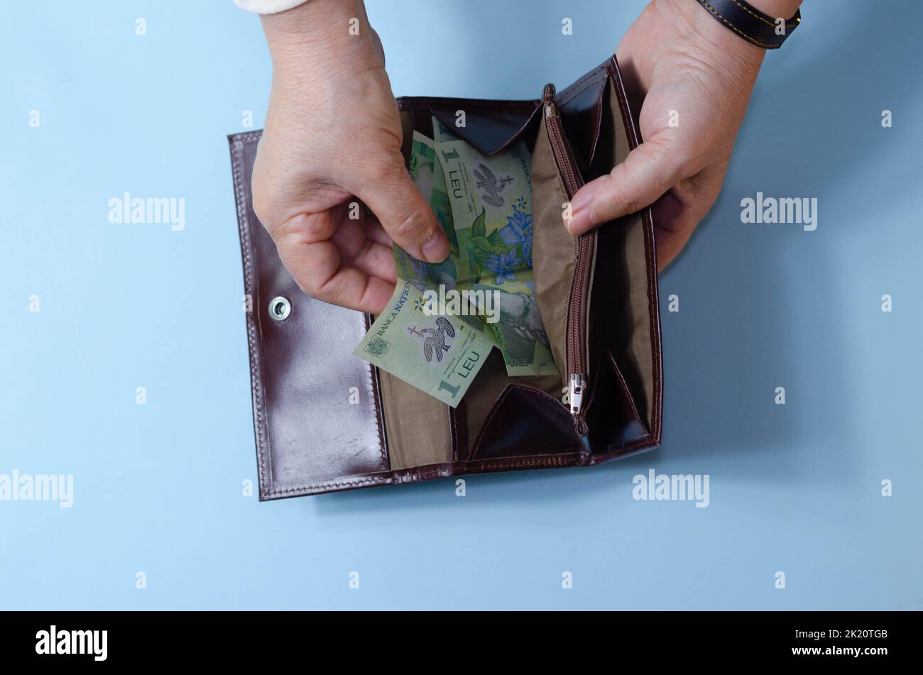 Hands of elderly woman with money ron on wallet on blue background ...