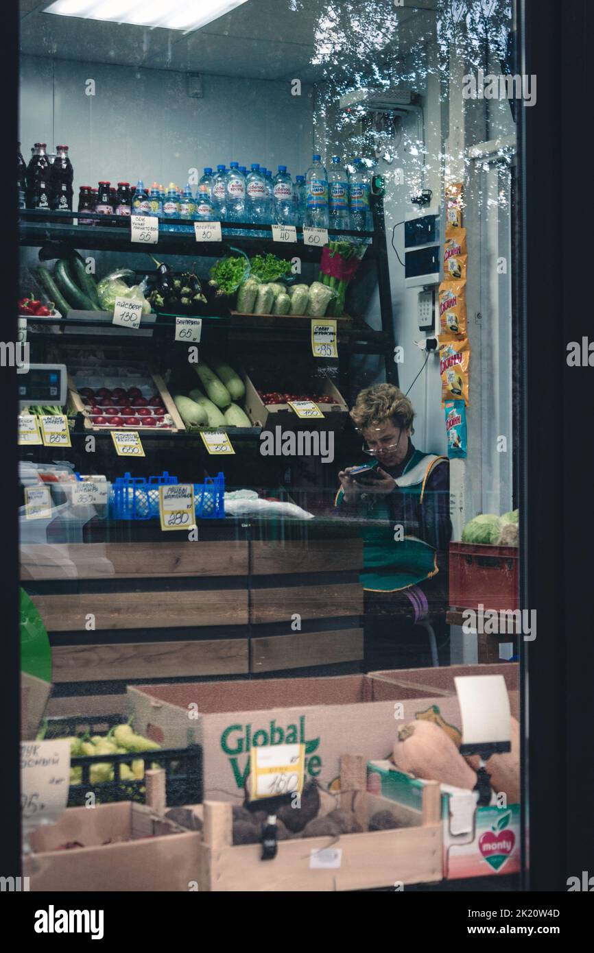A vertical shot of an elderly female salesperson sitting in a grocery ...