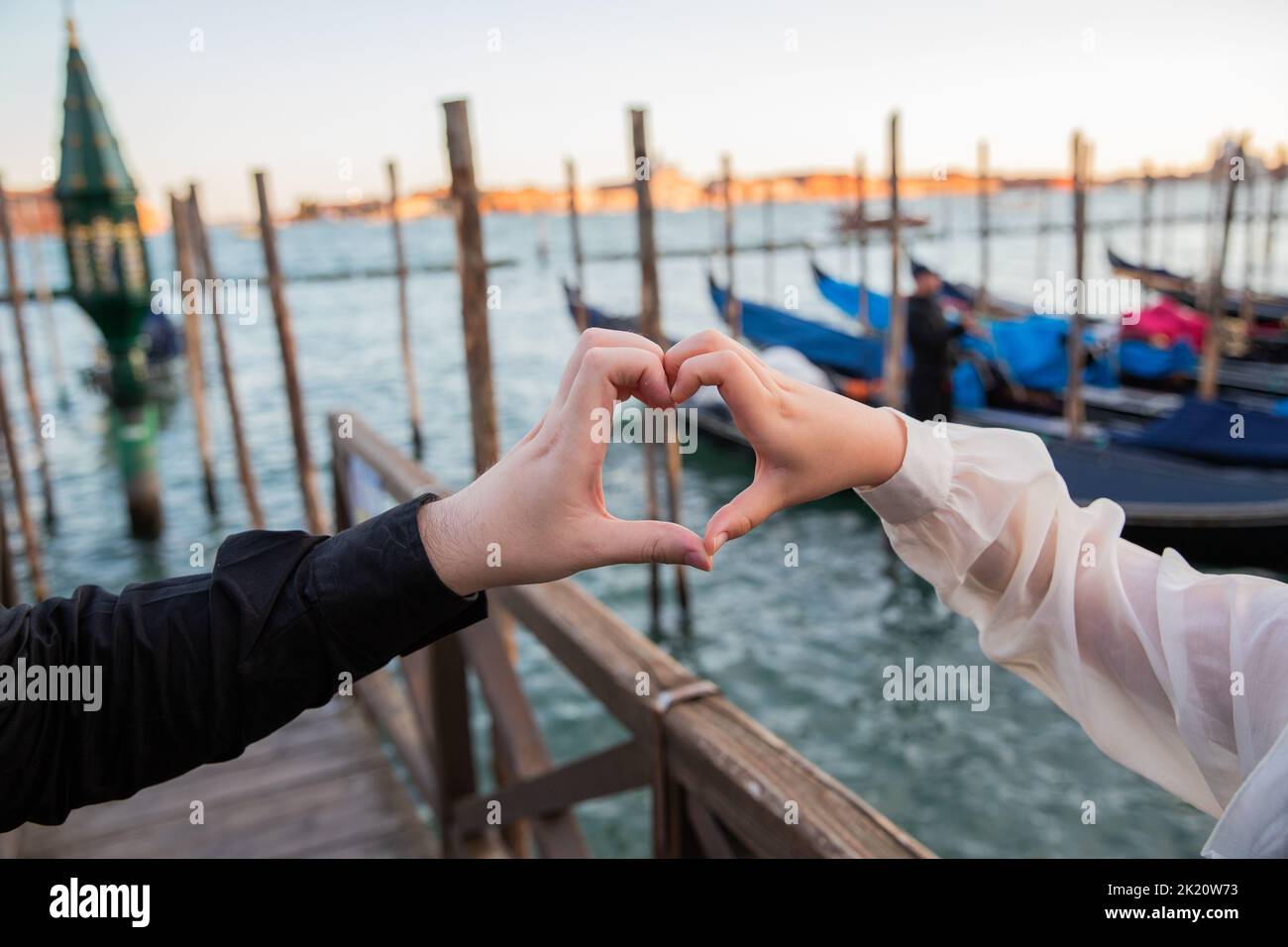 Hands of two lovers make a heart shape in Venice, gondolas in the ...