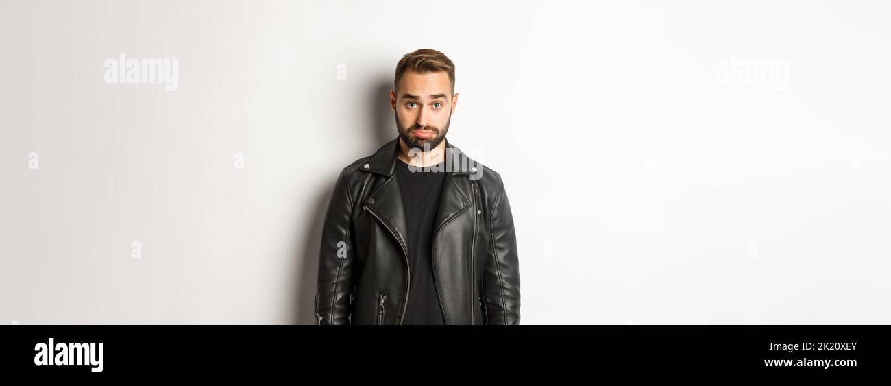 Sad and cute guy in leather black jacket pouting, looking silly at ...