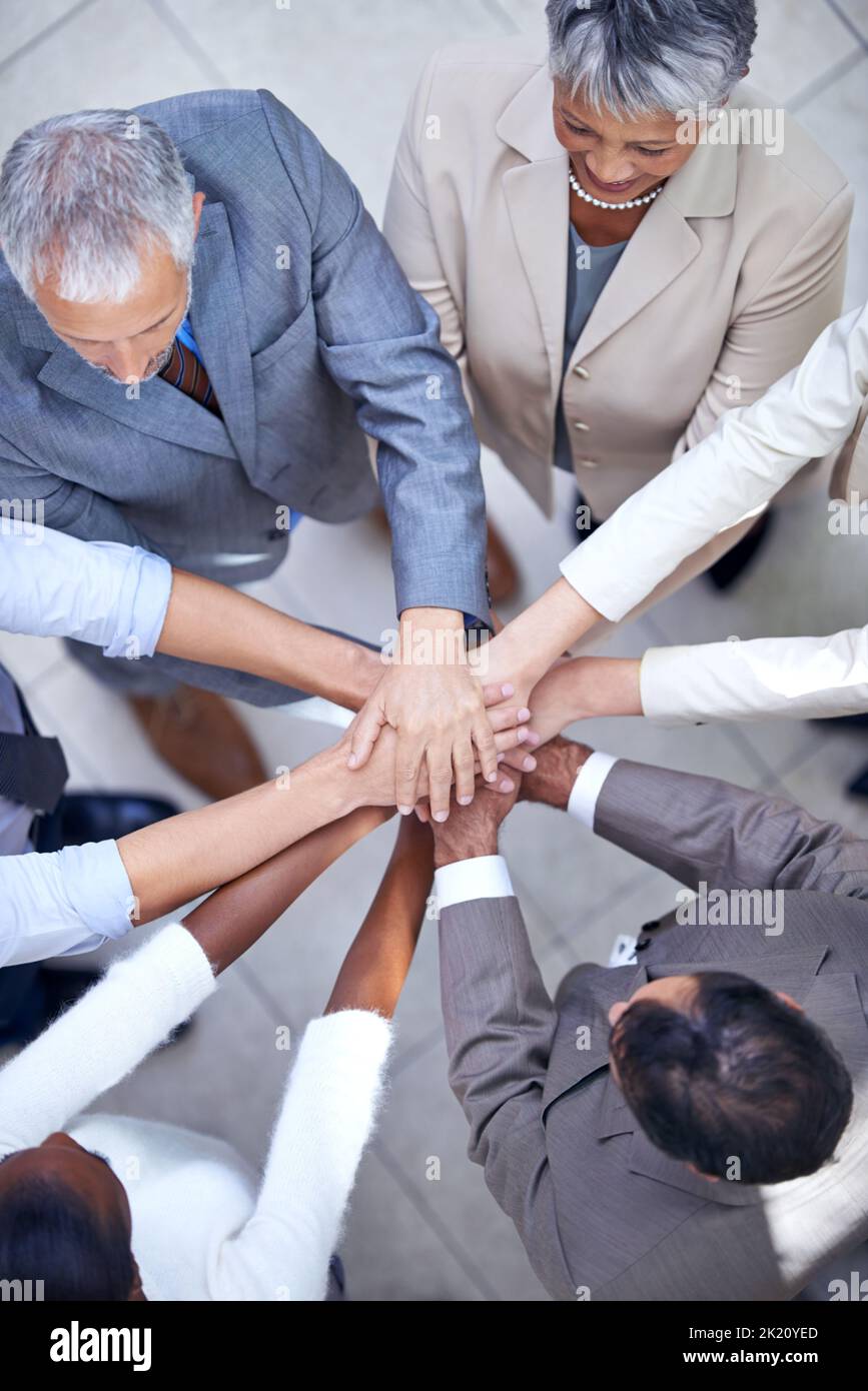 Together we will succeed. a group of coworkers with their hands in a ...