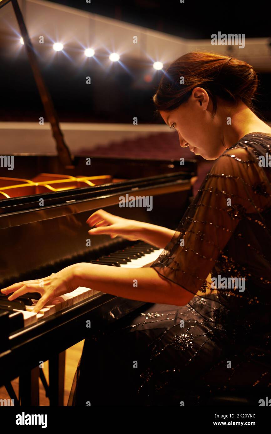 Entertaining the crowd. a young woman playing the piano during a ...