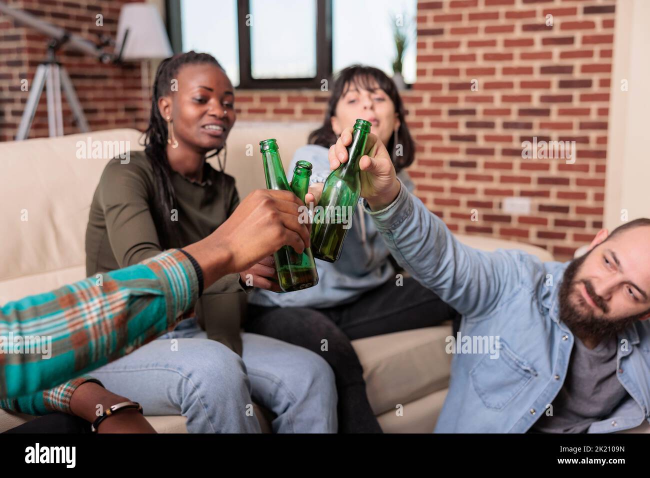 Men and women doing cheers gesture and clinking glass bottles of beer ...