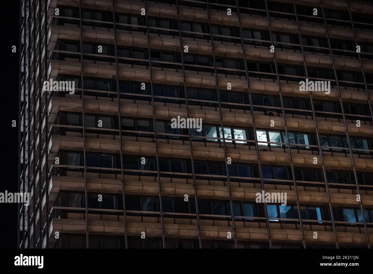 A high-rise building with some windows with burning light Stock Photo ...