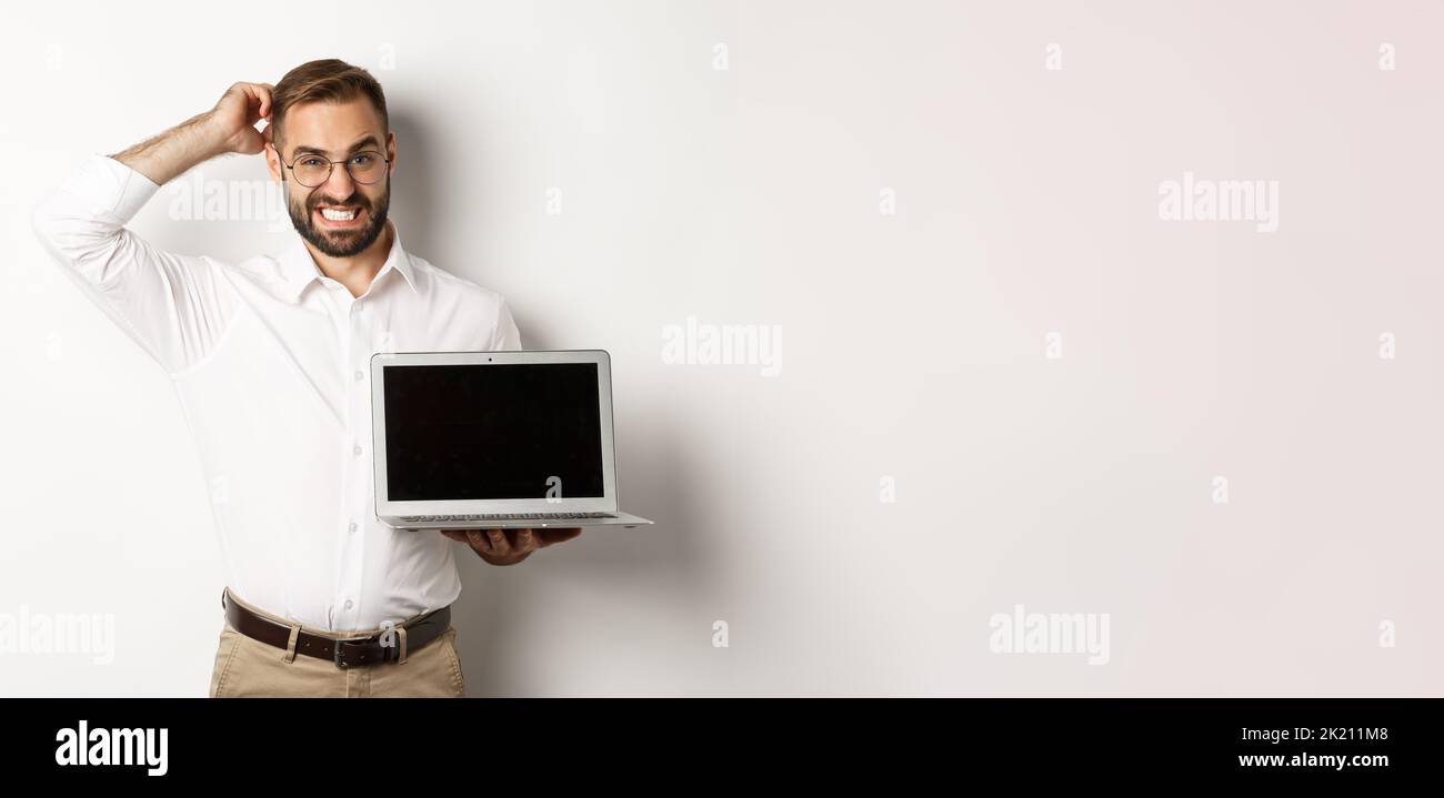 Awkward business man showing laptop screen and looking doubtful ...