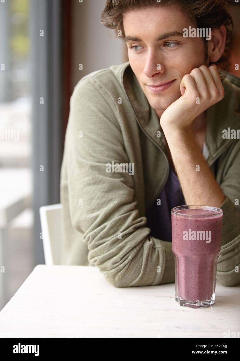 Waiting for my friend to join me. A young man drinking a cold beverage ...