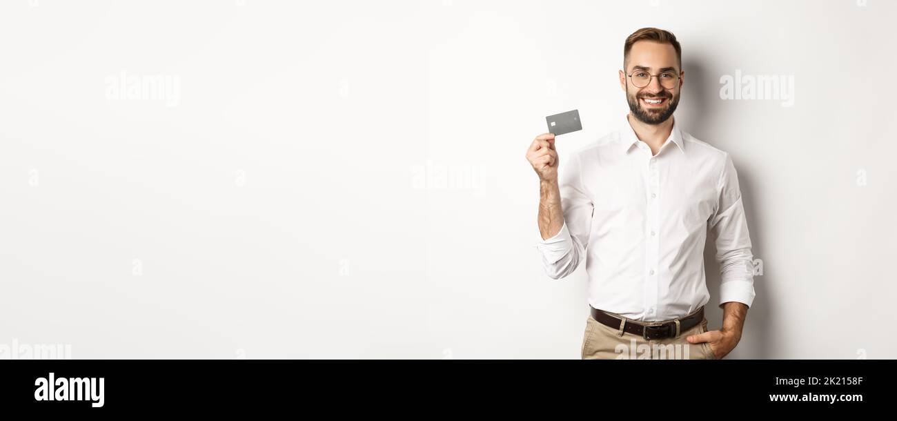 Handsome businessman showing his credit card, looking satisfied ...