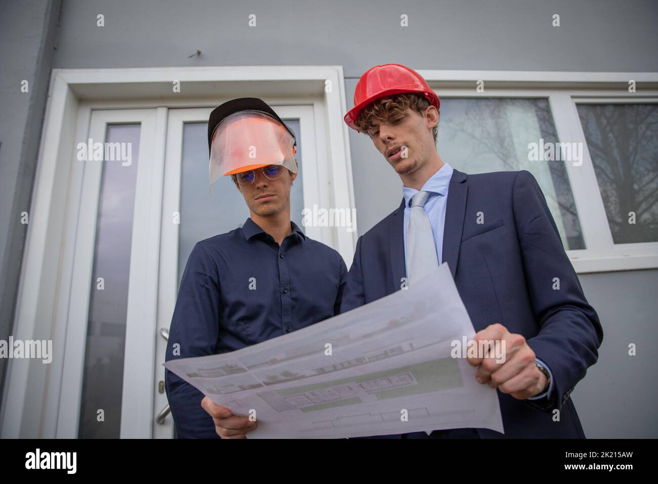 Two engineers at work look at the floor plan to set up the work to be ...