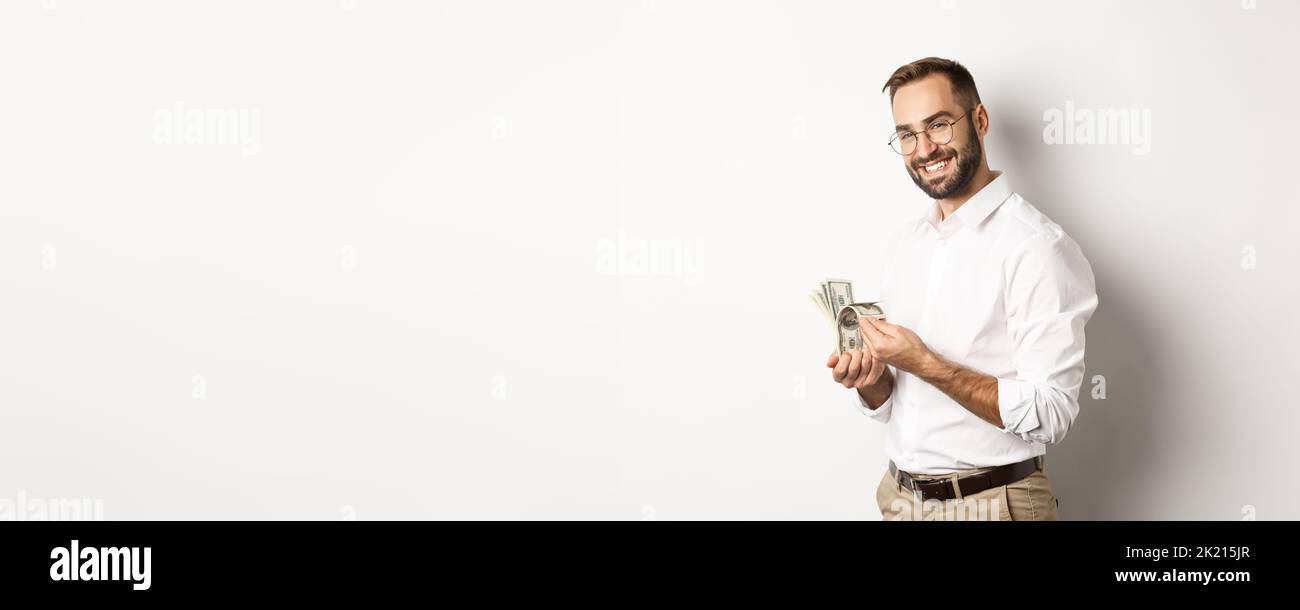 Successful business man counting money and smiling, standing against ...