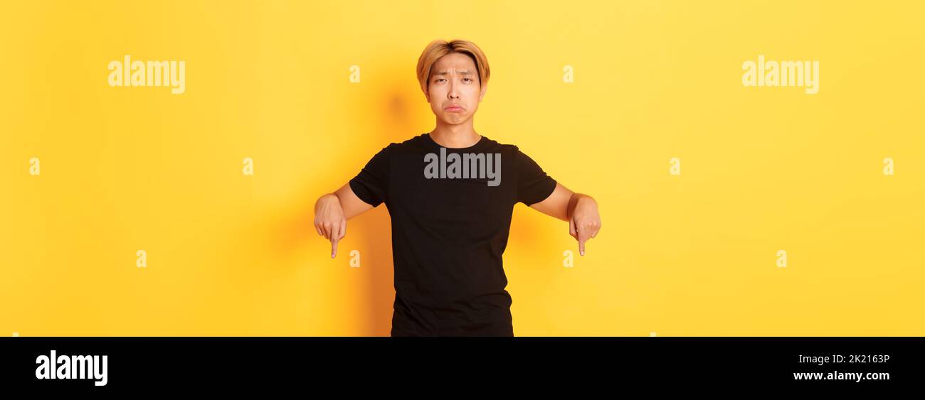 Portrait of disappointed gloomy asian guy, pouting upset and pointing ...