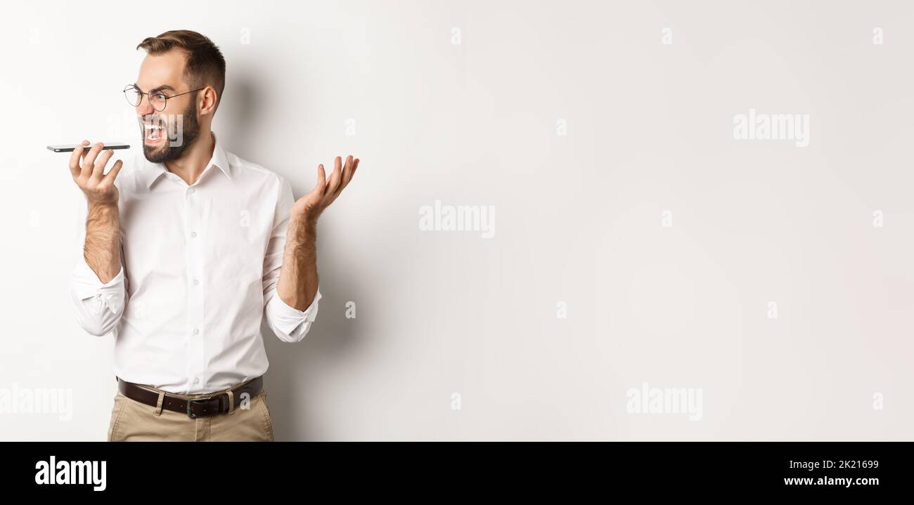 Angry business man shouting at speakerphone, record voice message in ...