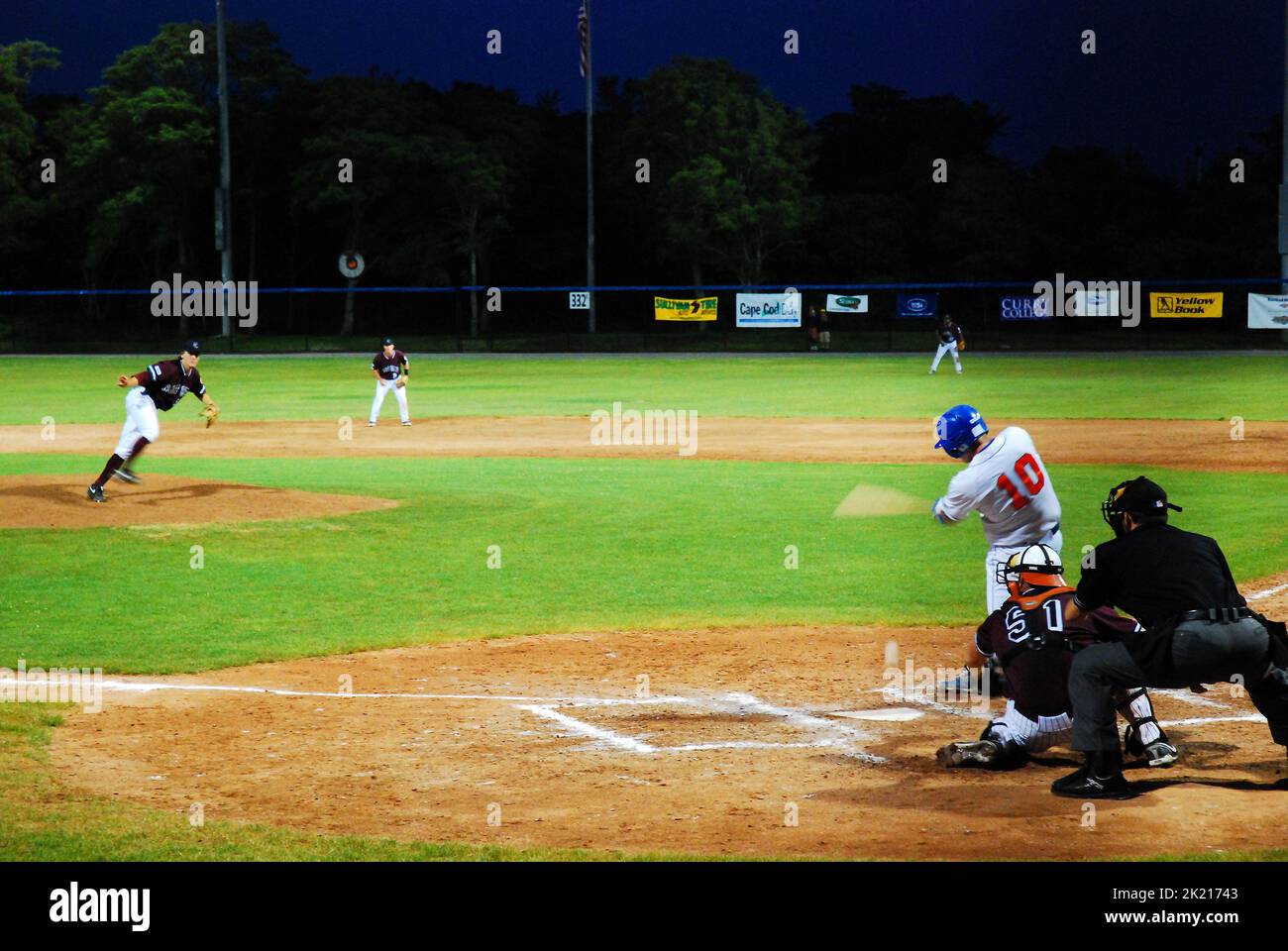 A batter takes a swing at a pitch at a night game in the Cape Cod ...