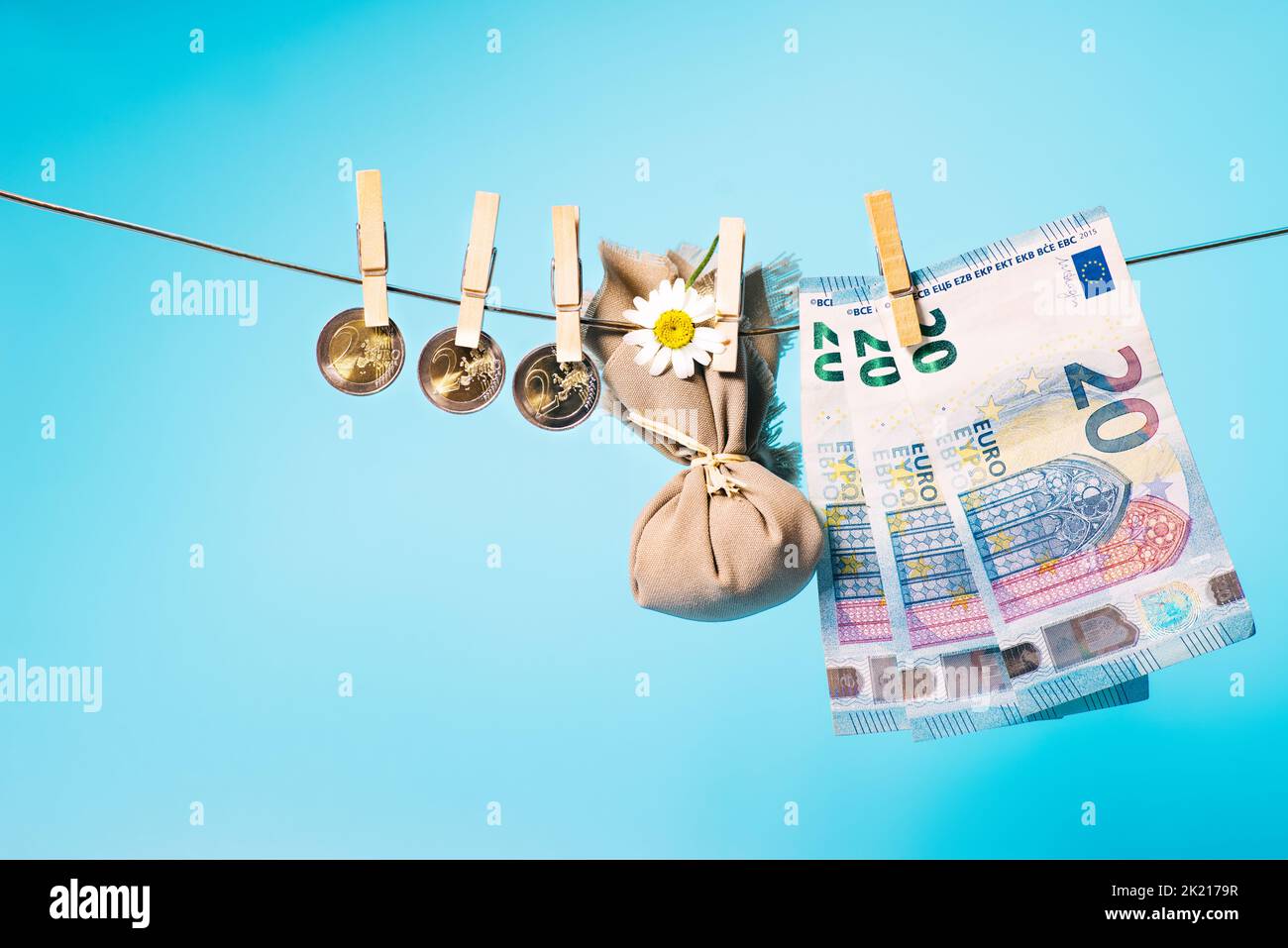 Coins on a rope on a blue background, euro bills, hung by wooden ...