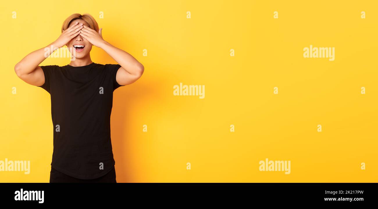 Portrait of amused and excited smiling blond guy shut eyes with palms ...