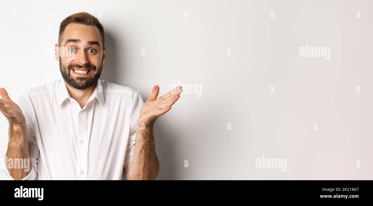 Close-up of awkward manager shrugging and smiling with sorry look ...