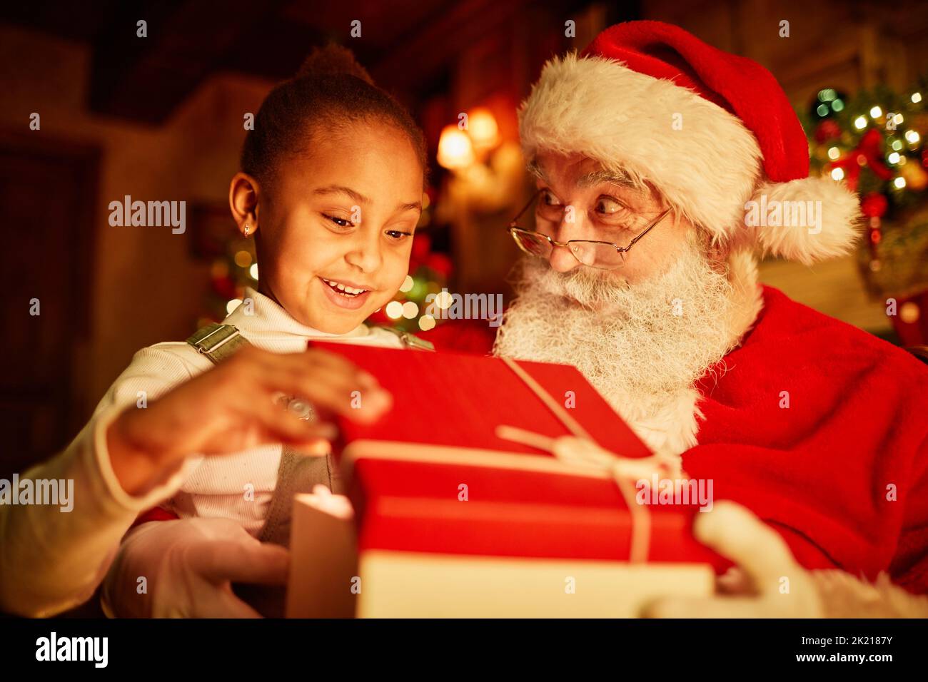 Portrait of cute little girl opening Christmas present with magic light ...