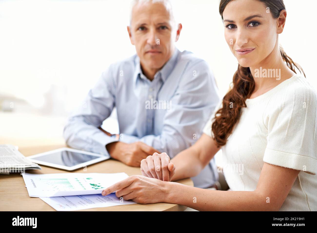 Getting the job done. two colleagues reading paperwork while sitting at ...