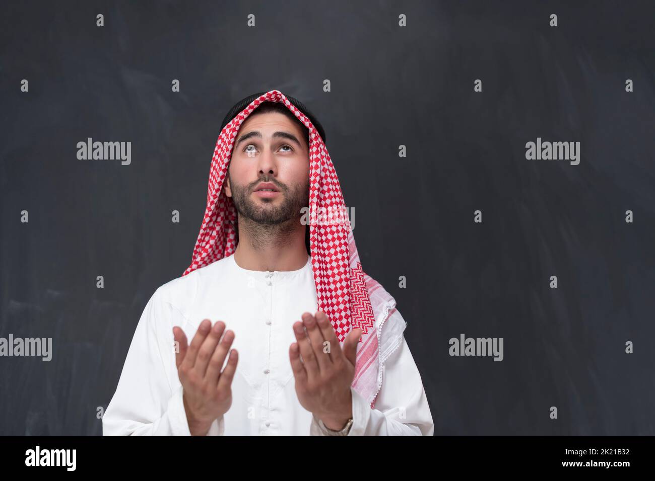 A young Arabian man in traditional clothes making a traditional prayer ...