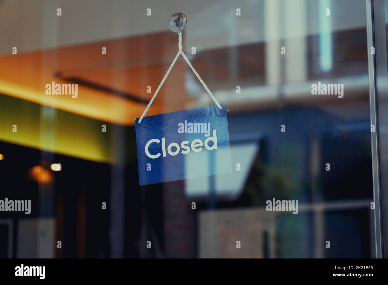 The closed sign hanging inside a glass door of the shop Stock Photo - Alamy