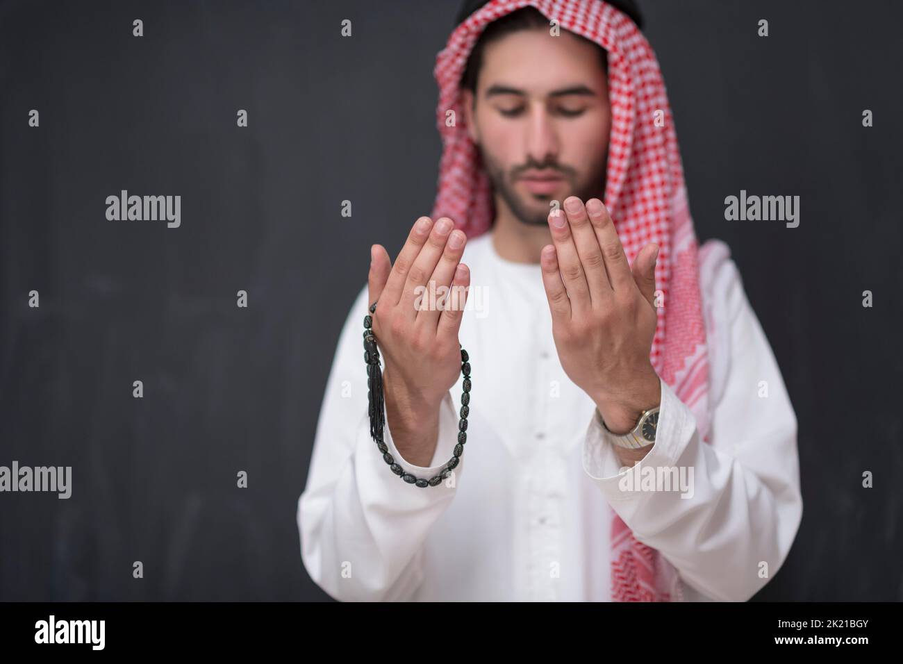 A young Arabian man in traditional clothes making a traditional prayer ...