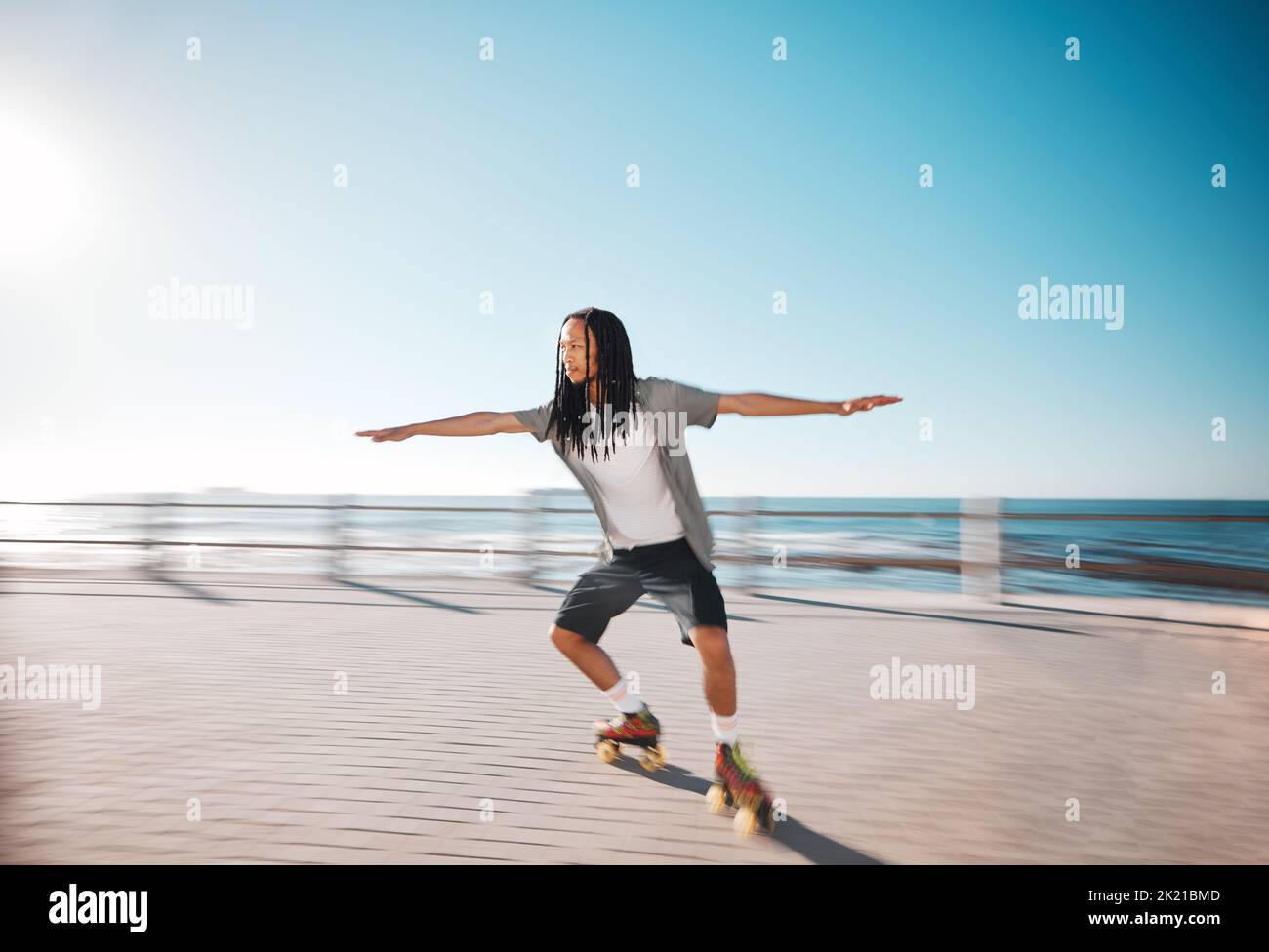Man roller skating on the promenade at the beach during a summer ...