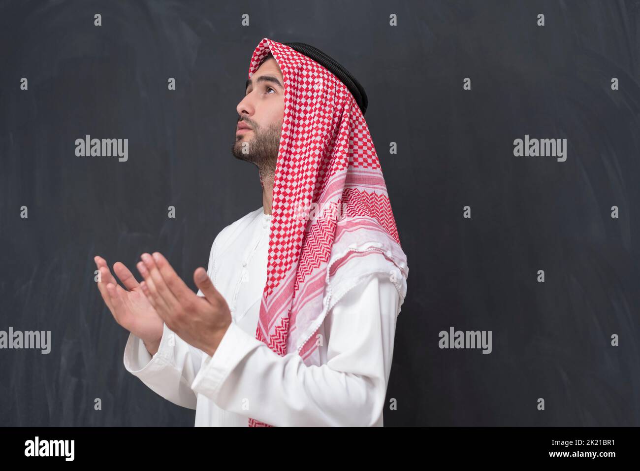 A young Arabian man in traditional clothes making a traditional prayer ...