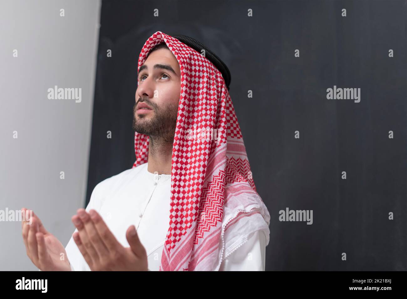 A young Arabian man in traditional clothes making a traditional prayer ...